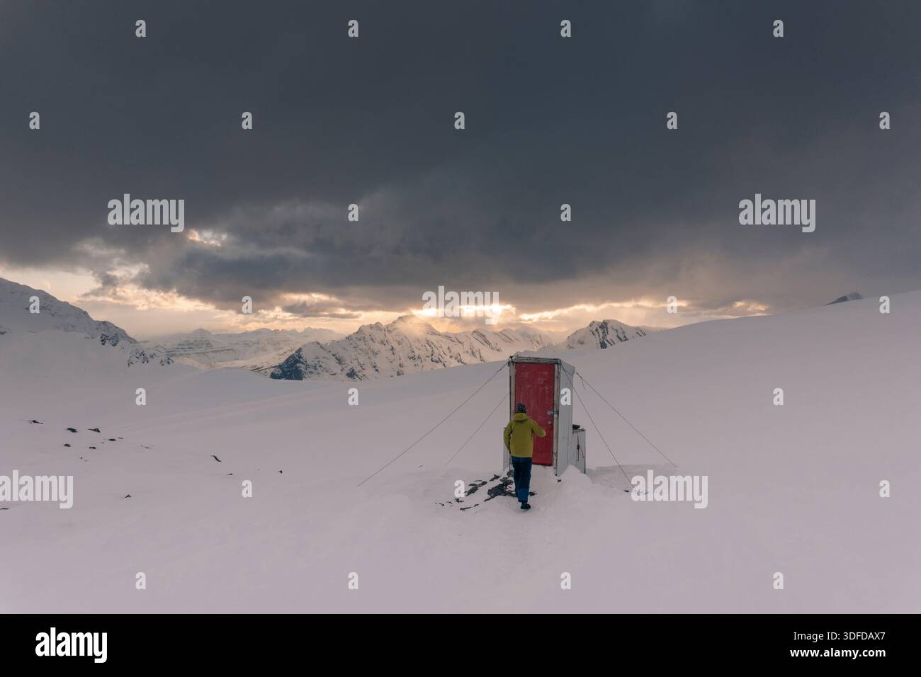 A man walks in front of an outhouse at a backcountry hut in the ...