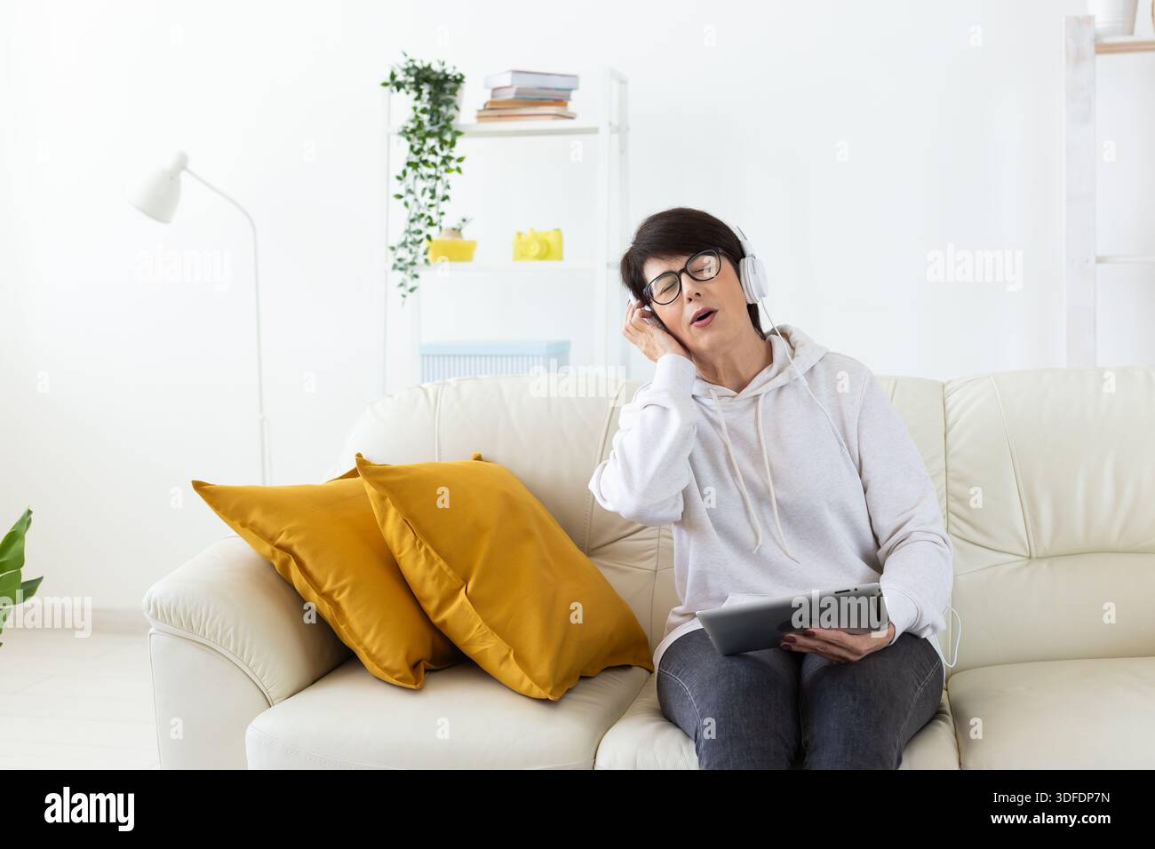 Woman listening to music with headphones on sofa in modern living room ...