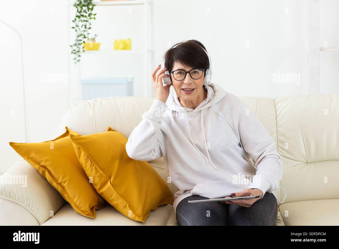 Woman listening to music with headphones on sofa in modern living room ...