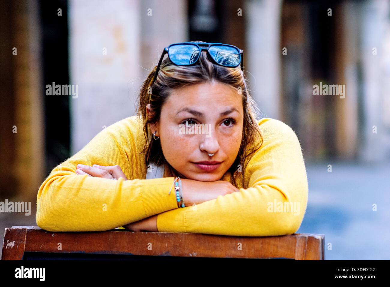 Young woman looking away, casually leaning forward with crossed arms ...
