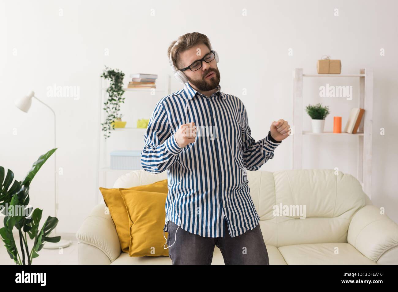 Man dancing while listening to music with headphones in living room ...