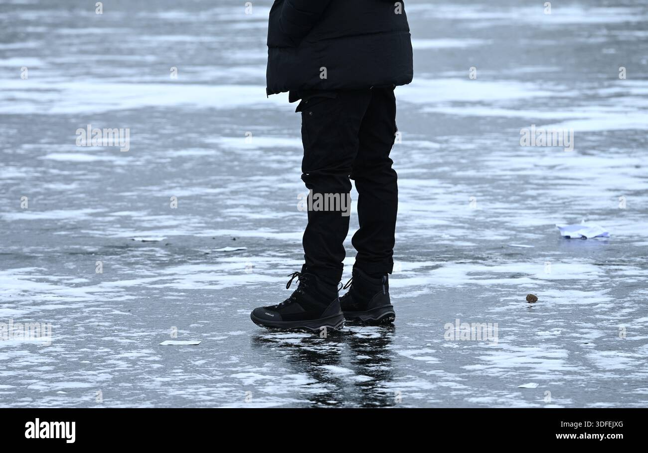 12 January 2026, Berlin: A man stands on the frozen Spree at Treptower ...