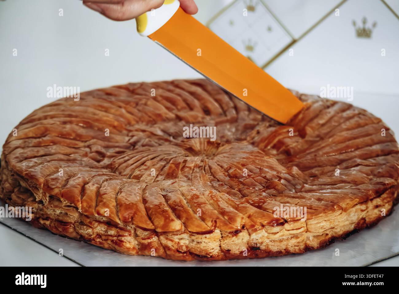 A woman cutting a galette des rois, a traditional French pastry made of ...