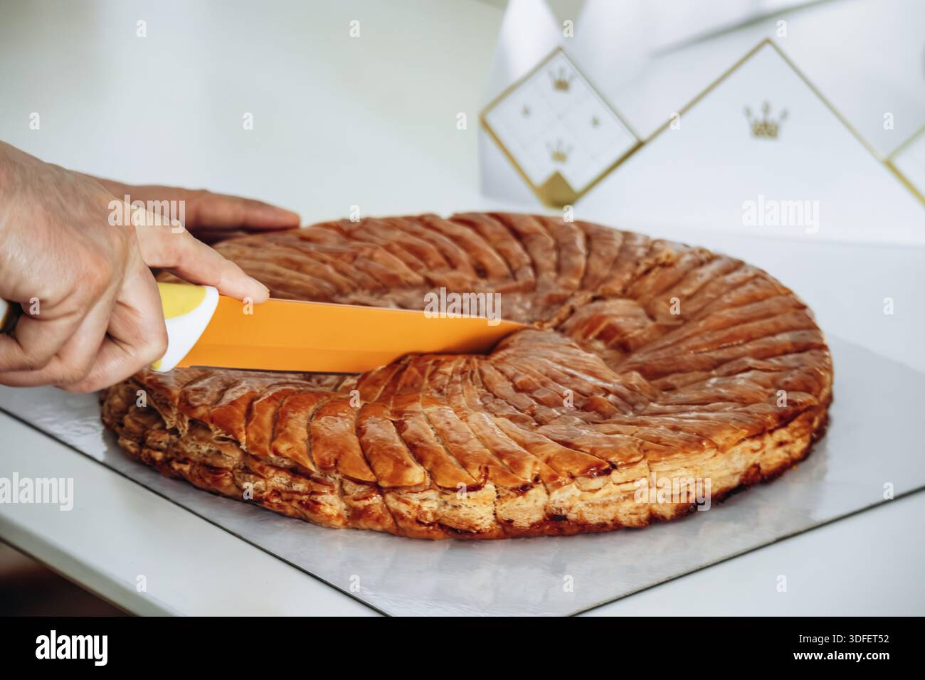 A woman cutting a galette des rois, a traditional French pastry made of ...