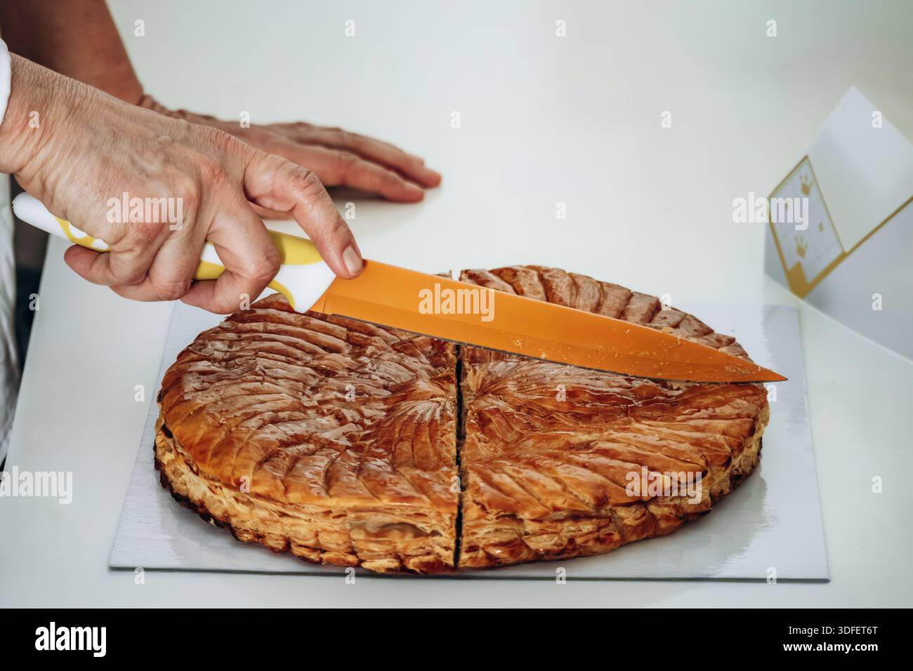 A woman cutting a galette des rois, a traditional French pastry made of ...