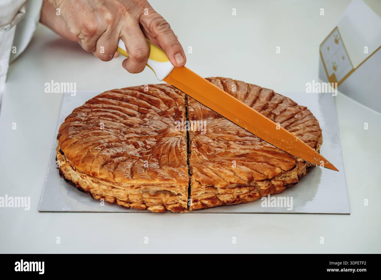 A woman cutting a galette des rois, a traditional French pastry made of ...