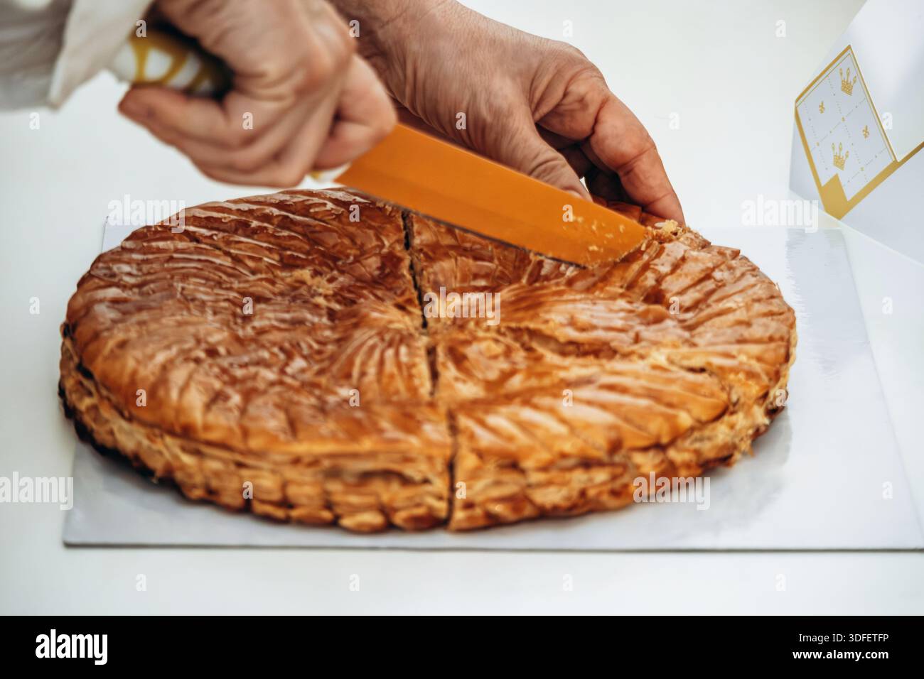 A woman cutting a galette des rois, a traditional French pastry made of ...