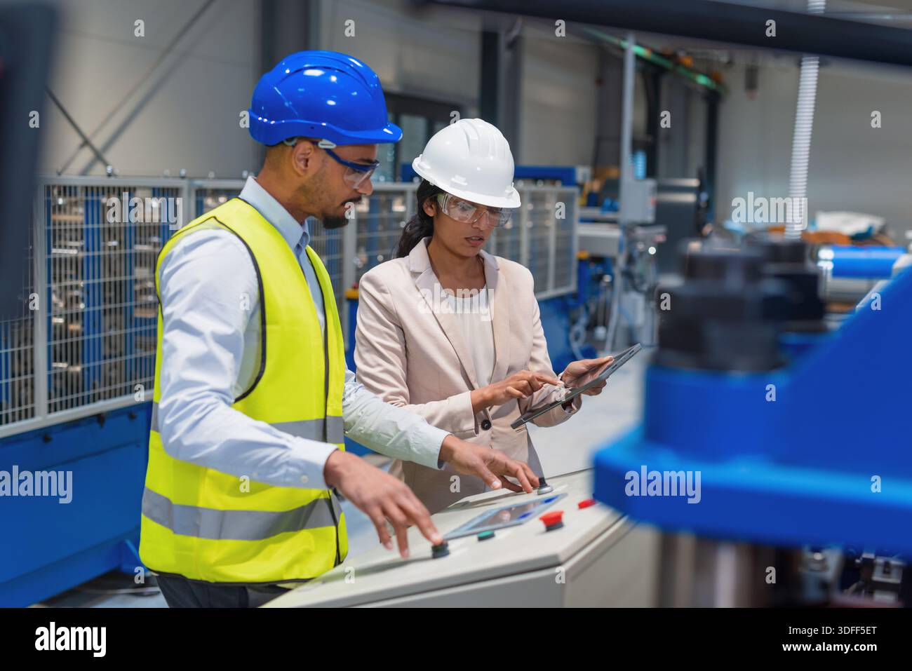 Female manager guides male worker on production process in busy factory ...
