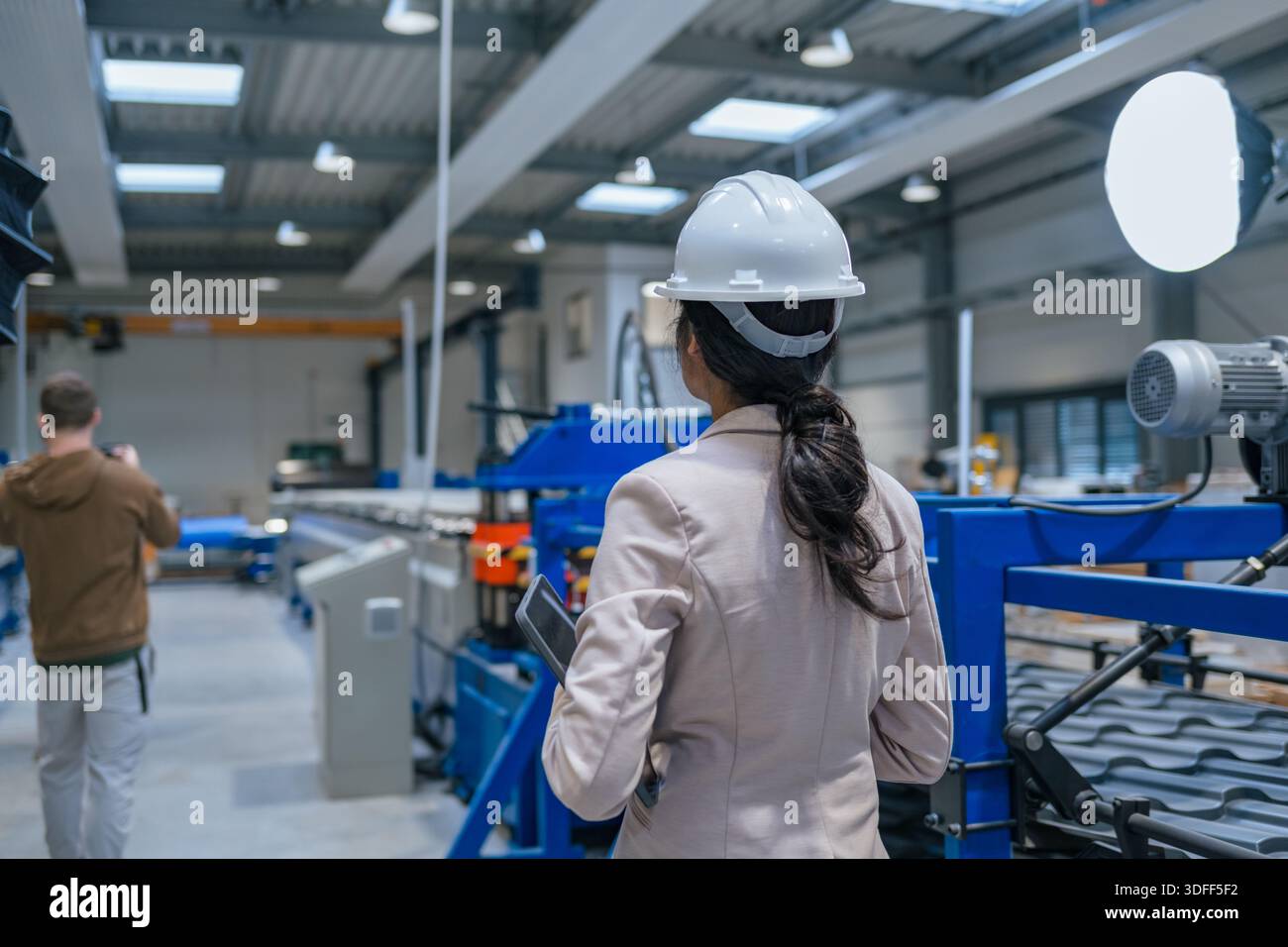 A female manager oversees a production process in a metal manufacturing ...