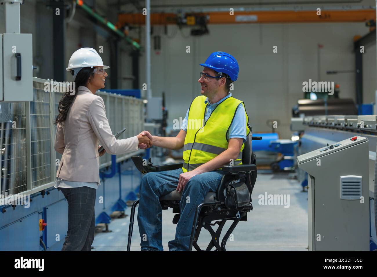 A female manager supervises production while a male worker in a ...