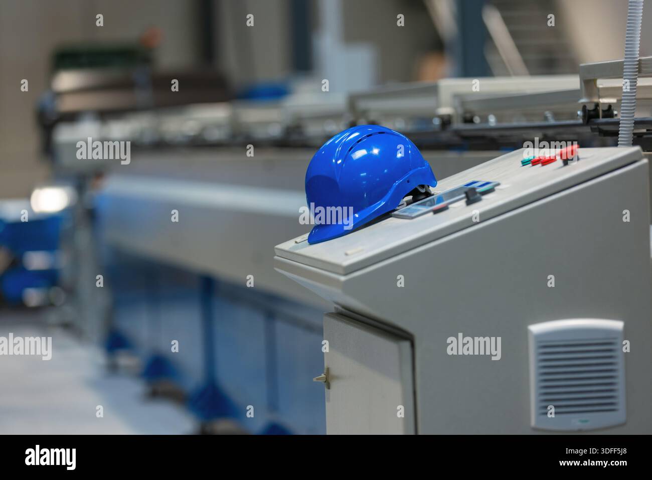 A hard hat sits on a control panel in an empty production line within a ...