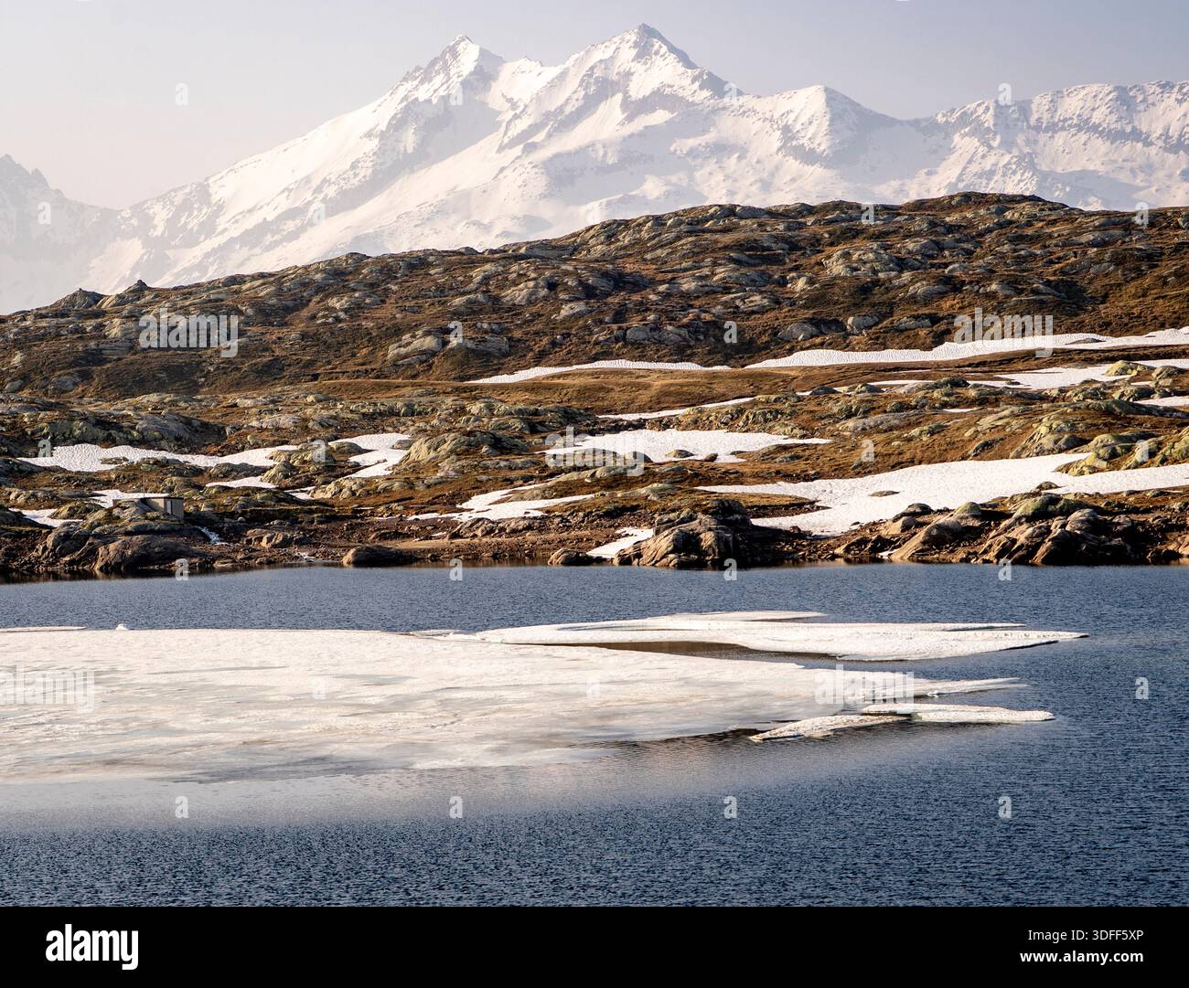 Snow-capped mountains and partially frozen lake in a serene landscape ...