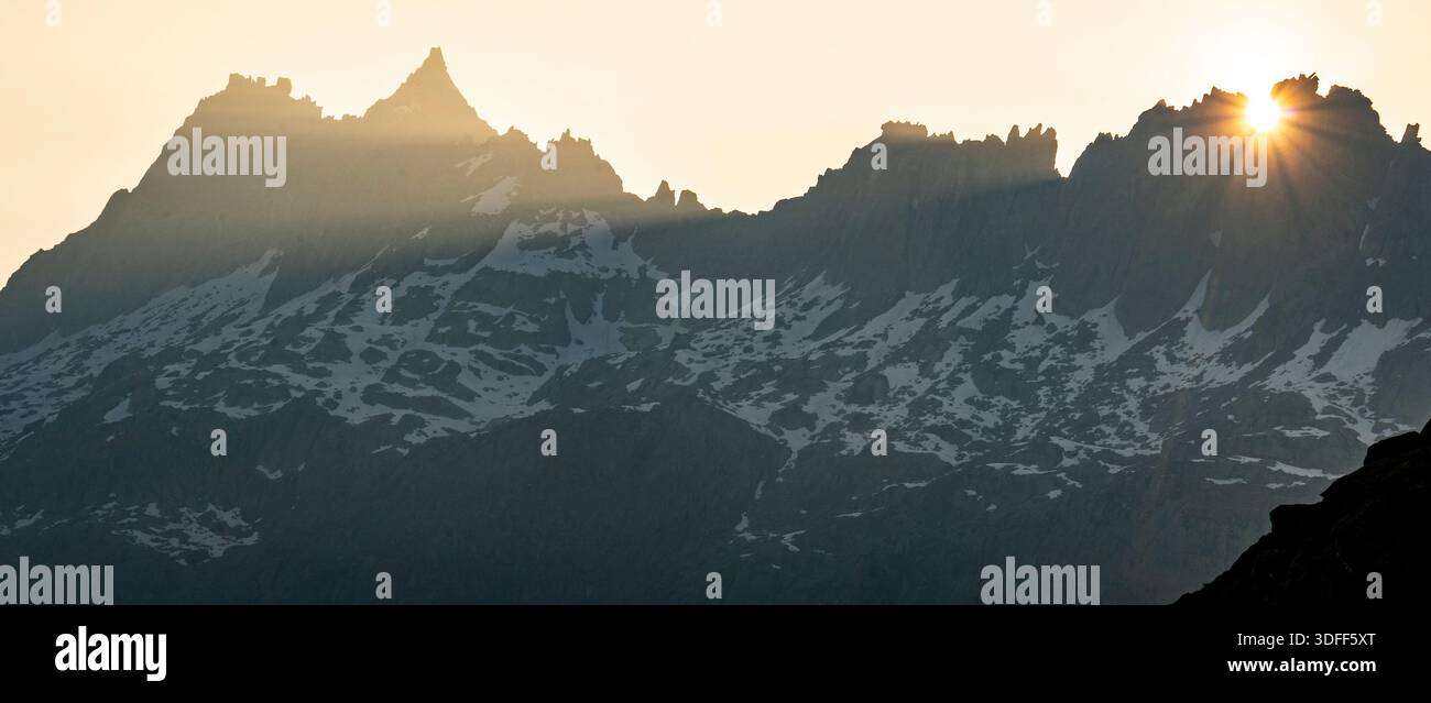 Sunrise over jagged mountain peaks with snow patches Stock Photo - Alamy