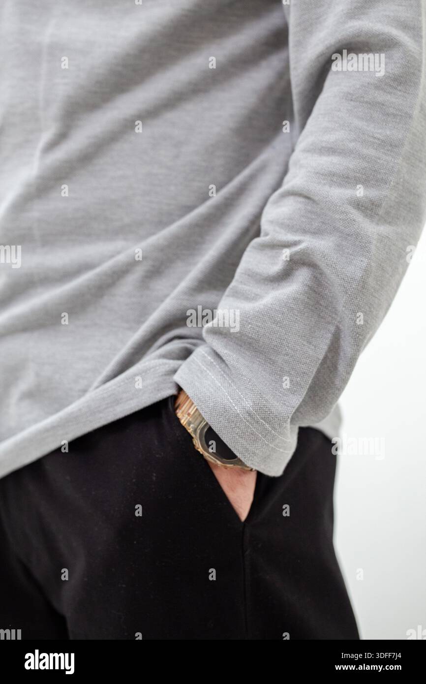 Side view of man in grey t-shirt with hand in pocket of black pants ...