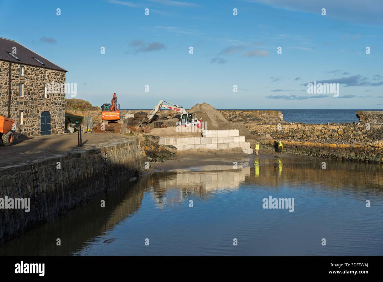 Workers use JCB diggers to repair storm damage at Portsoy Harbour in ...