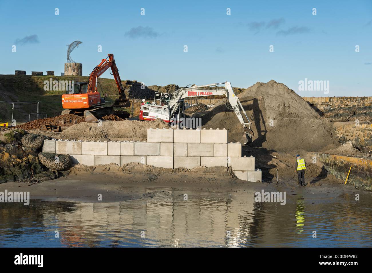 Workers are repairing storm damage to Portsoy Harbour in Scotland. JCB ...
