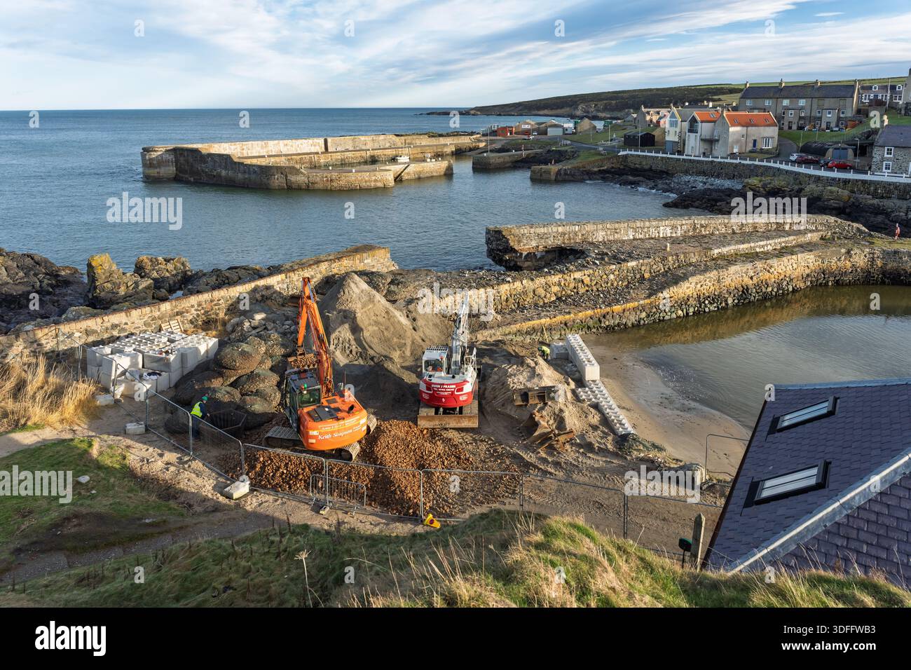 Workers use JCB diggers to rebuild the damaged areas of Portsoy Harbour ...