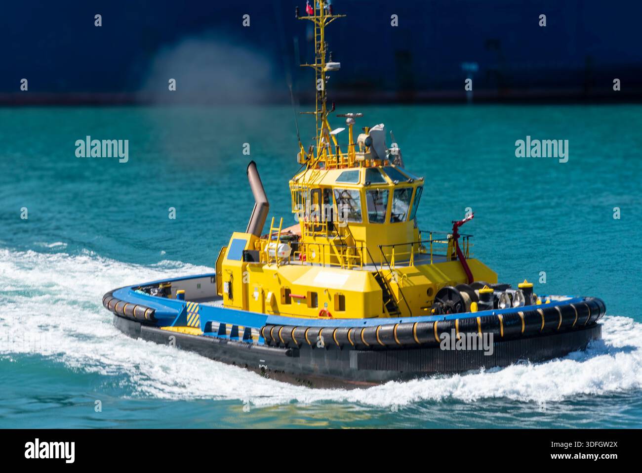 Harbor tugboat with yellow superstructure operating in port waters ...