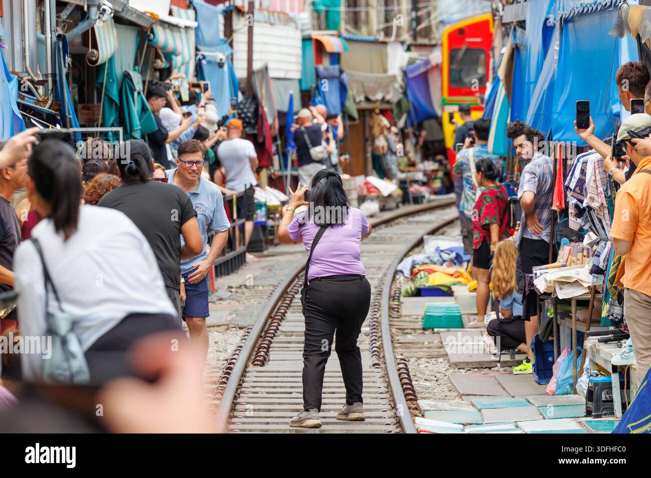 Samut Songkhram, June 14, 2025. Tourists walk along the railway track ...