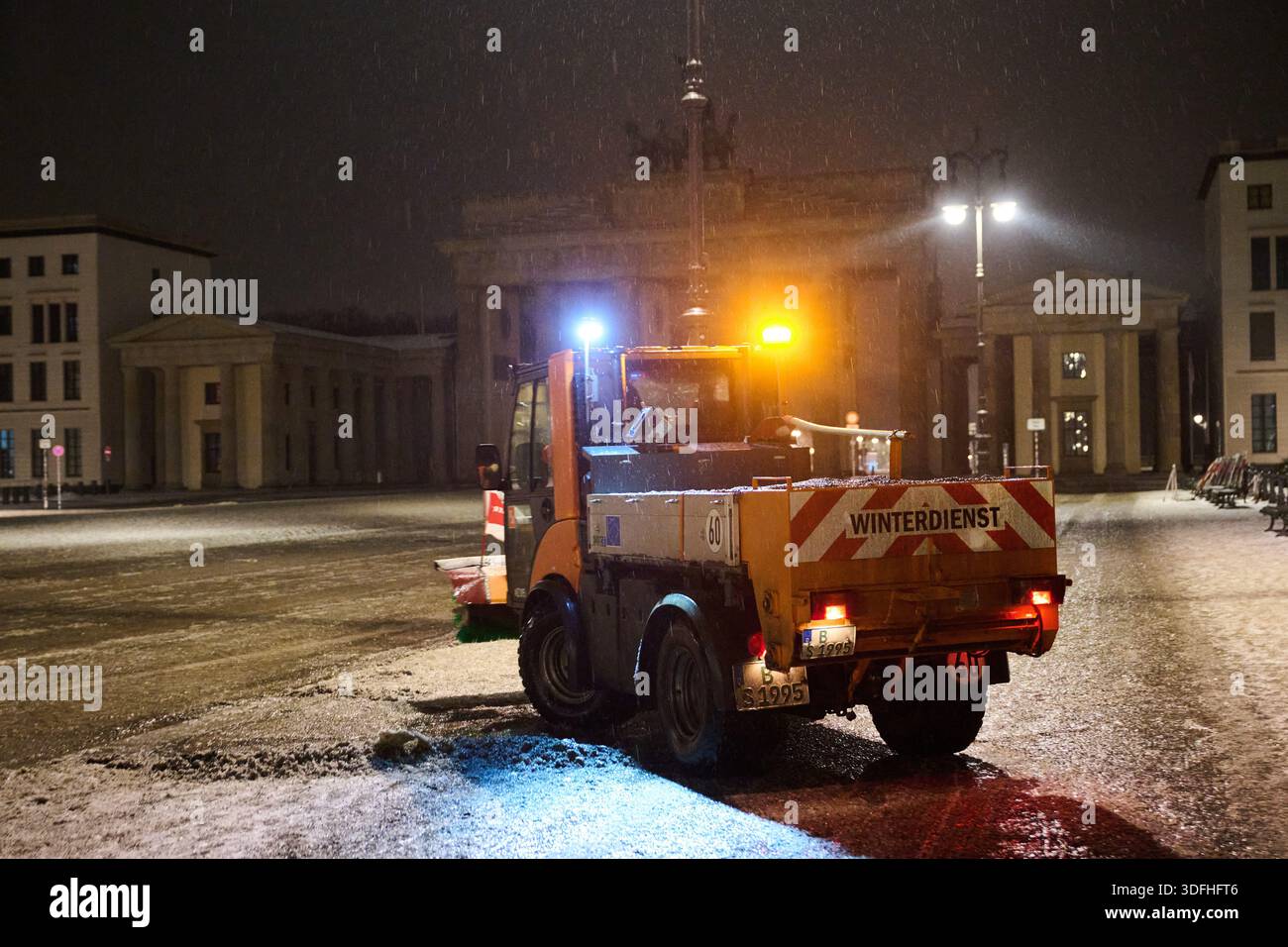 13 January 2026, Berlin: A BSR gritting vehicle grits at Brandenbuger ...
