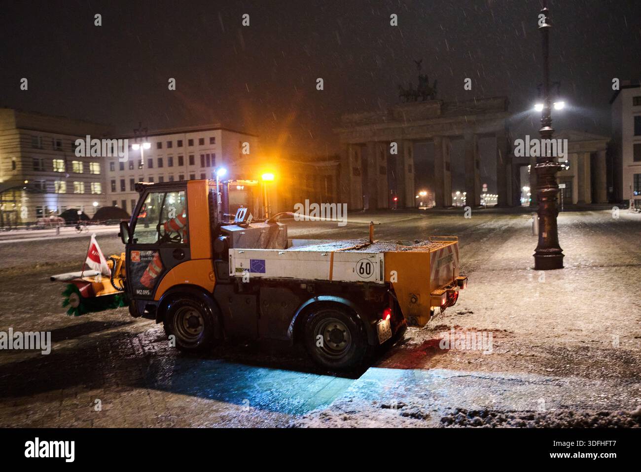 13 January 2026, Berlin: A BSR gritting vehicle grits at Brandenbuger ...