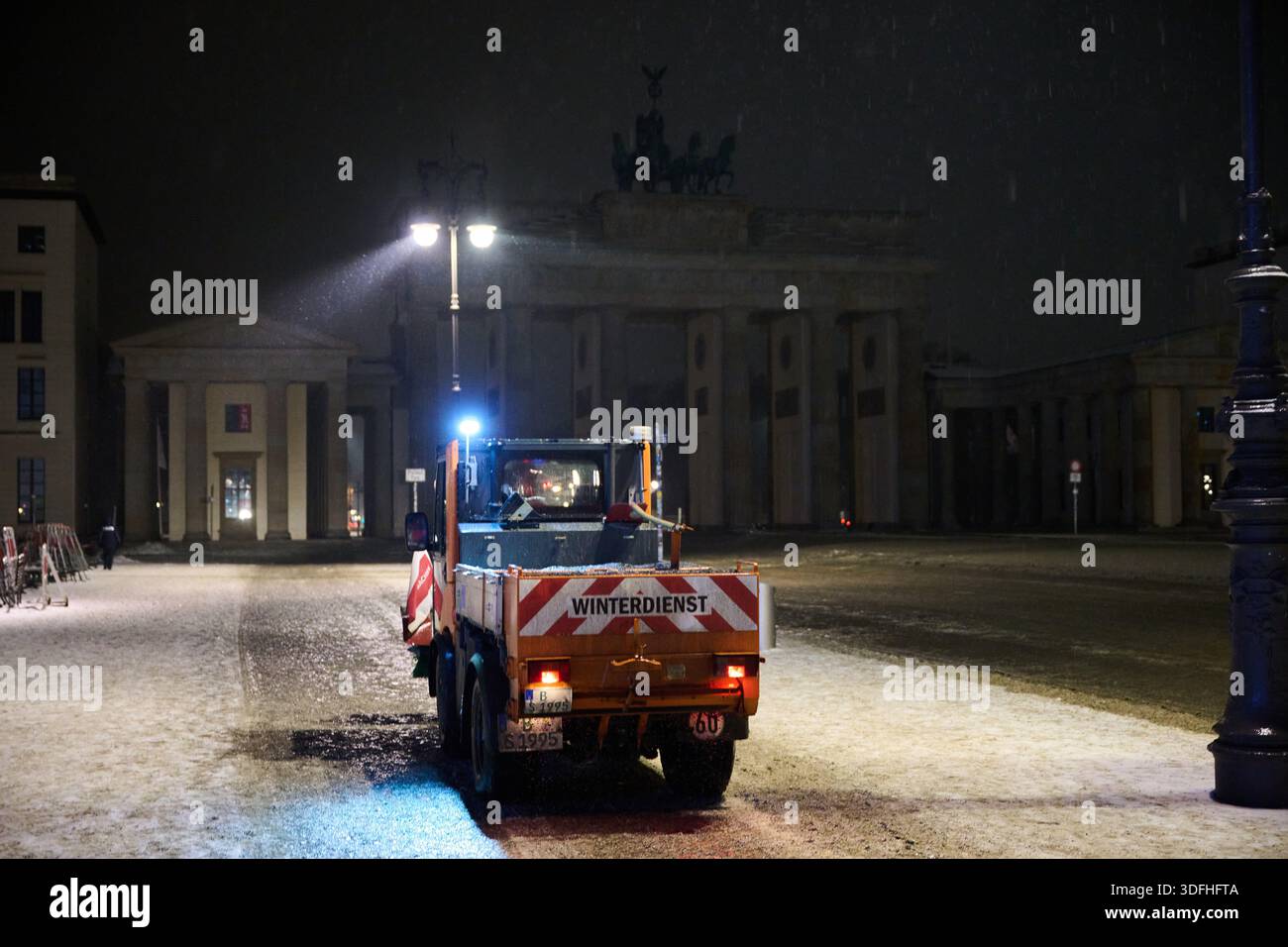 13 January 2026, Berlin: A BSR gritting vehicle grits at Brandenbuger ...