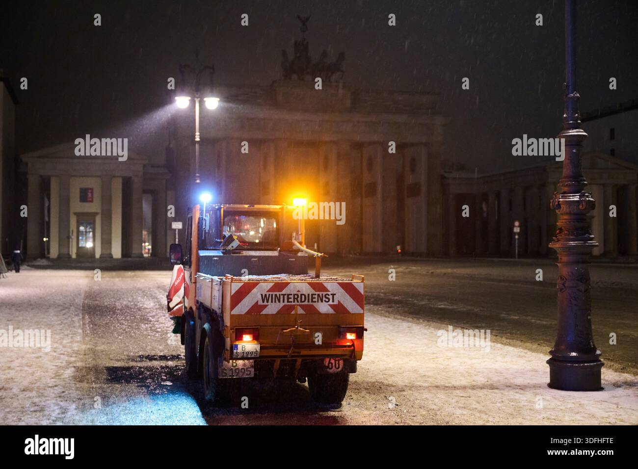 13 January 2026, Berlin: A BSR gritting vehicle grits at Brandenbuger ...