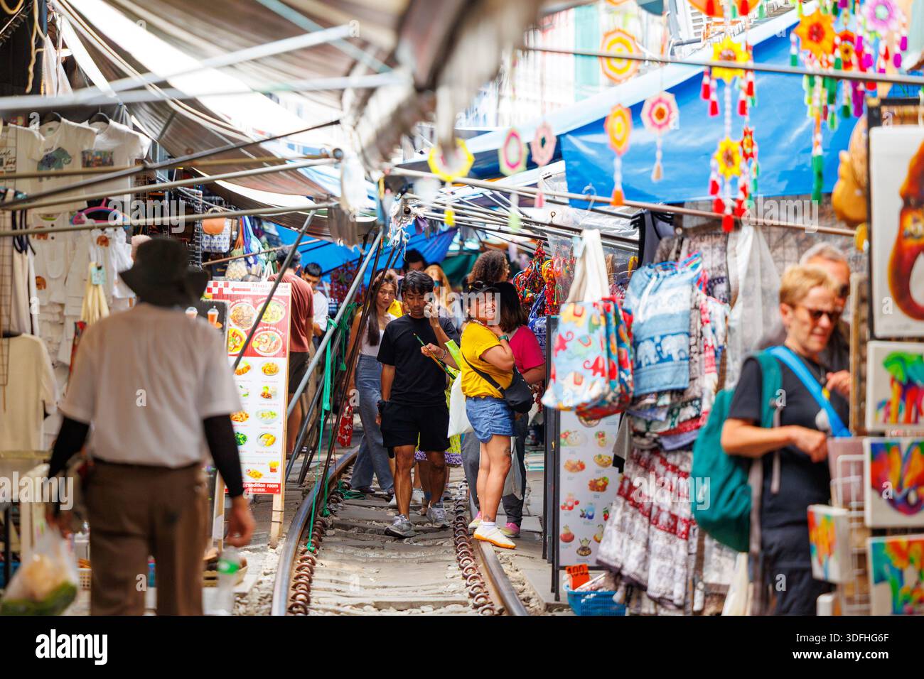 Samut Songkhram, June 14, 2025. Tourists walk along the railway track ...