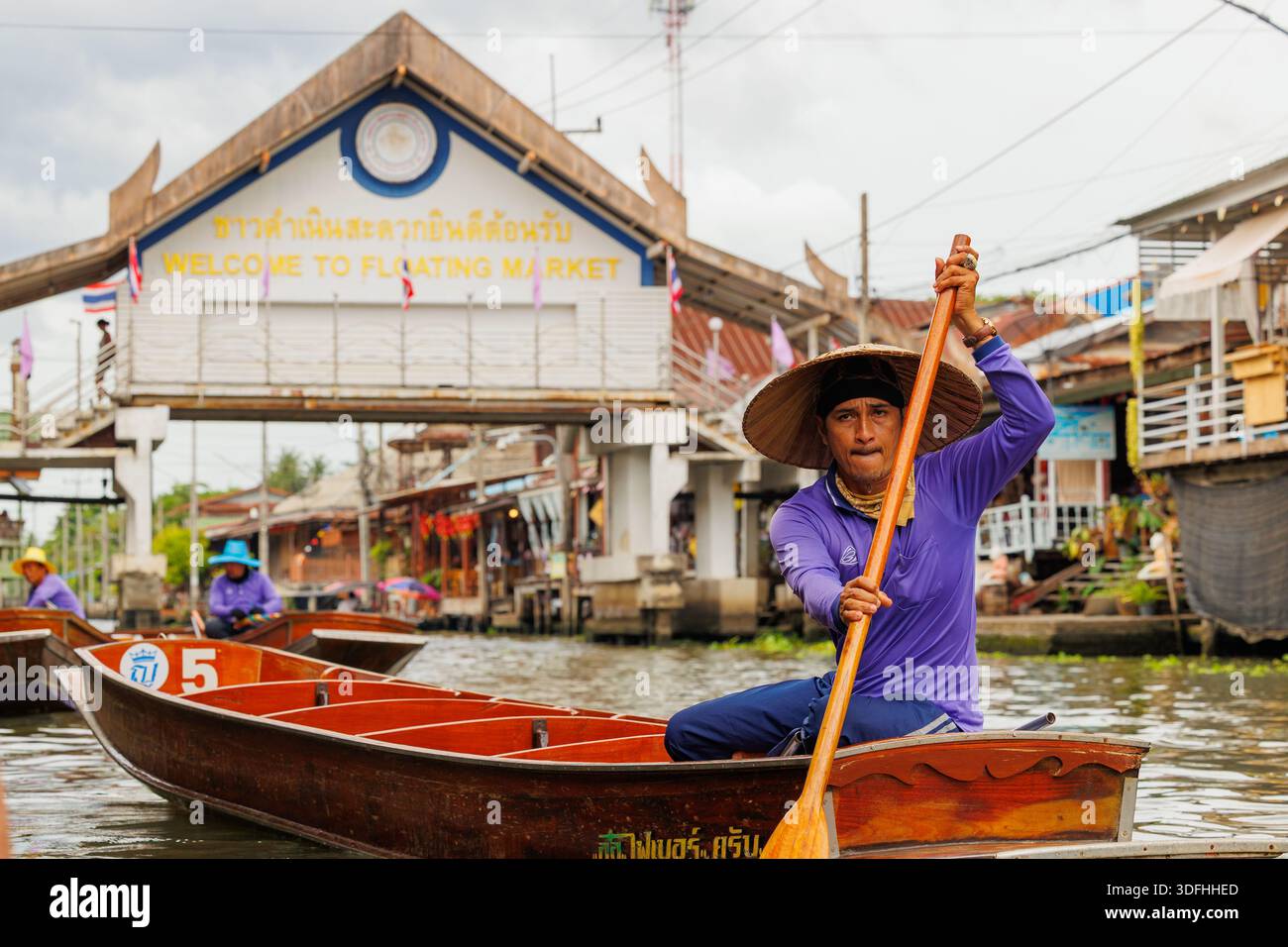 Damnoen Saduak, June 14, 2025. Boat operator in foreground with Welcome ...