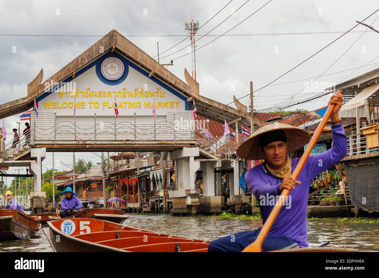 Damnoen Saduak, June 14, 2025. Boat operator in foreground with Welcome ...