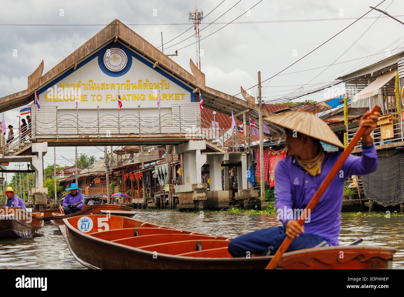 Damnoen Saduak, June 14, 2025. Boat operator in foreground with Welcome ...