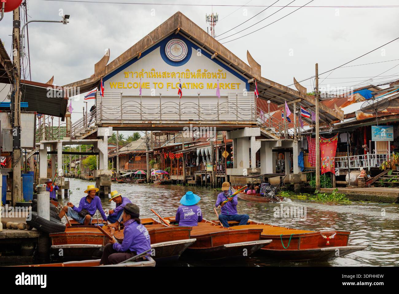 Damnoen Saduak, June 14, 2025. Boat operator in foreground with Welcome ...