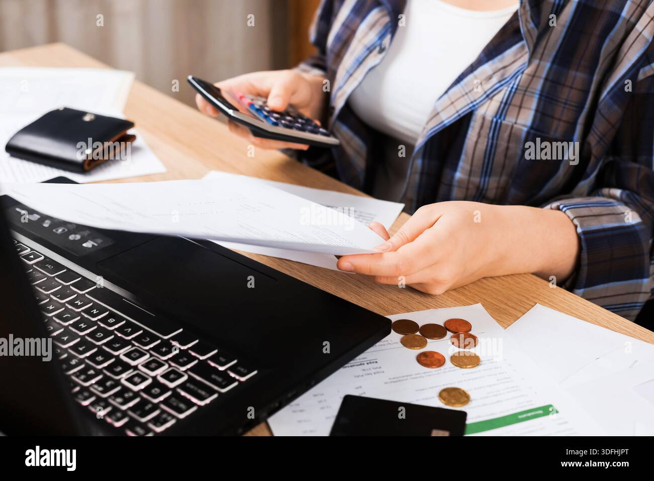 Woman checking bills and using a calculator near a laptop. Household ...