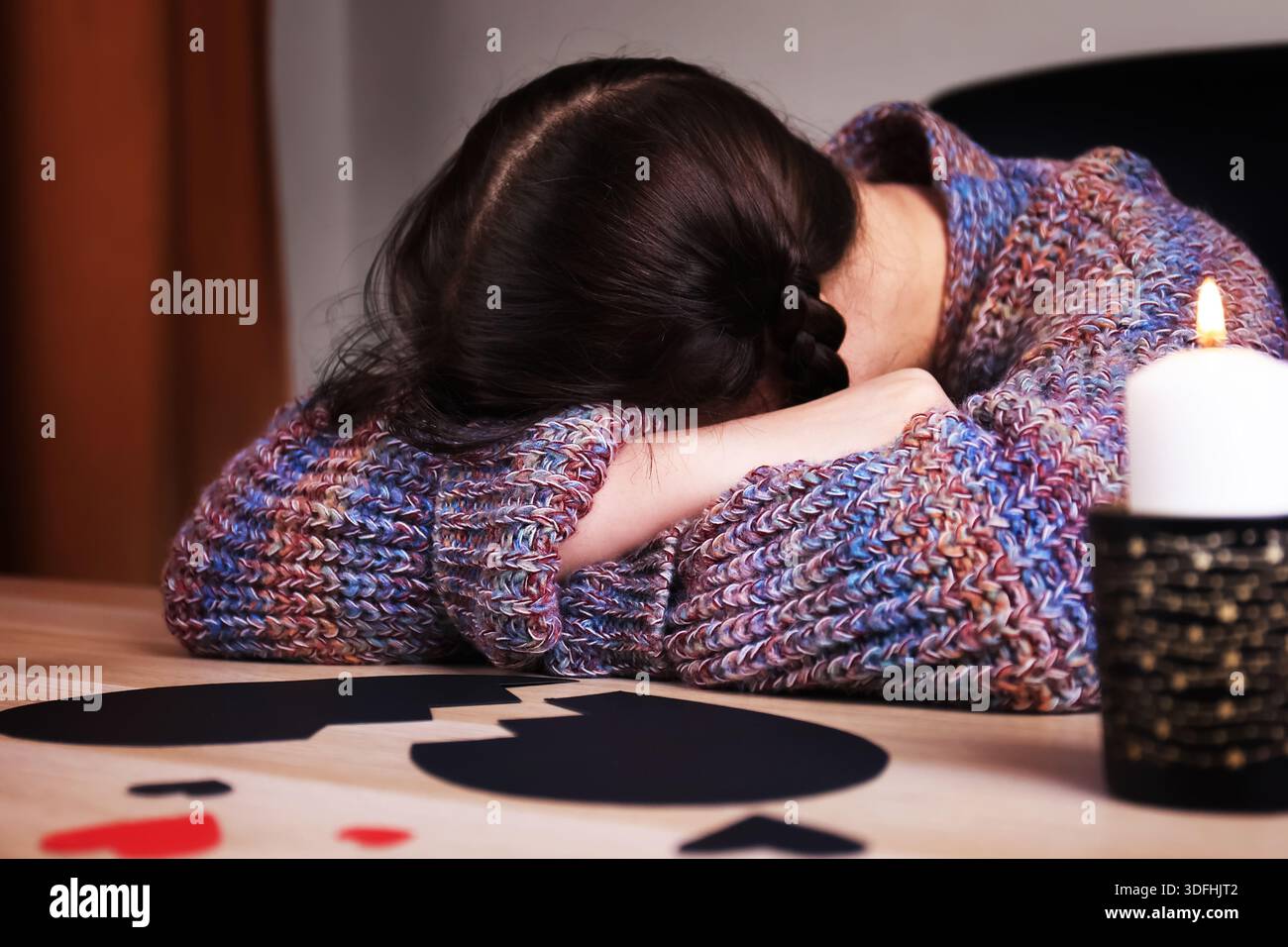 Sad woman lying head down on arms near a broken black heart. Lonely ...