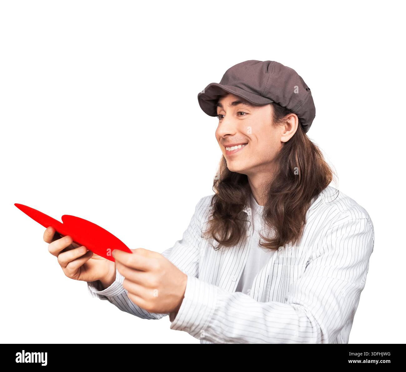Smiling long-haired man in a cap holding a red paper heart. Happy ...