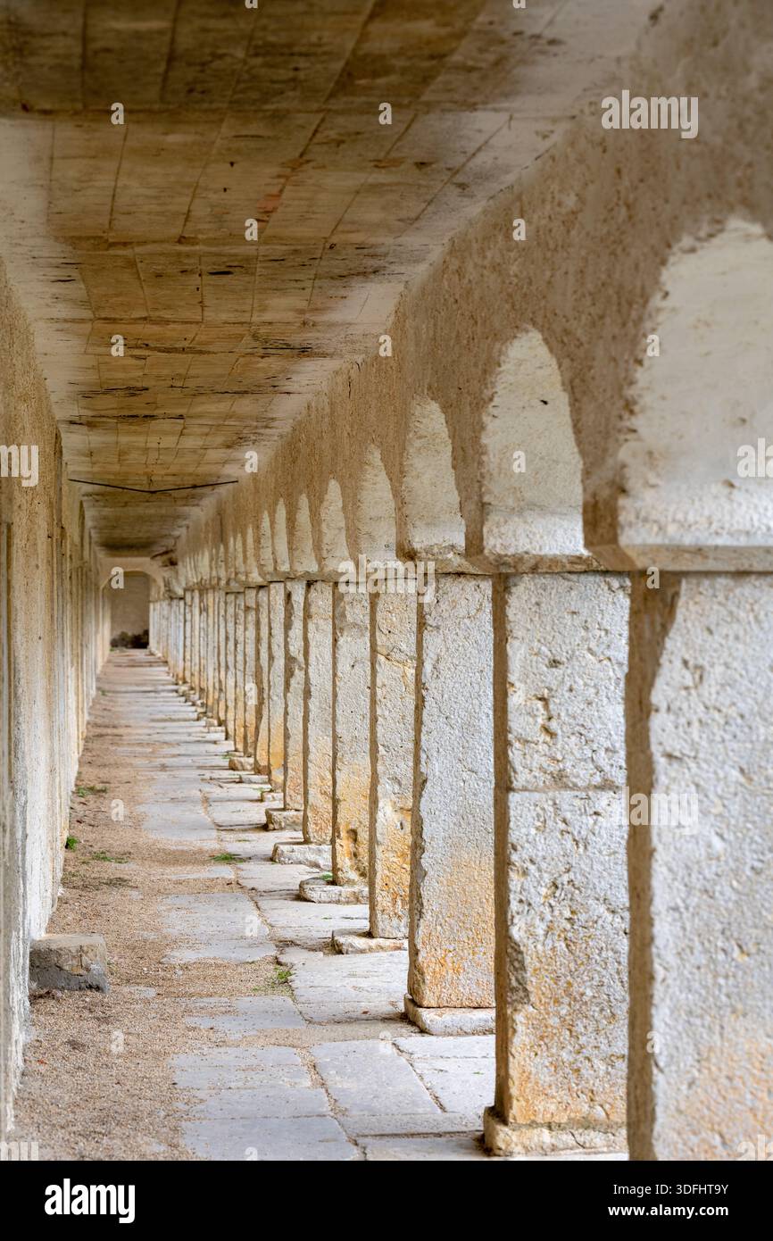 Stone columns form a long arched corridor within the sanctuary complex ...
