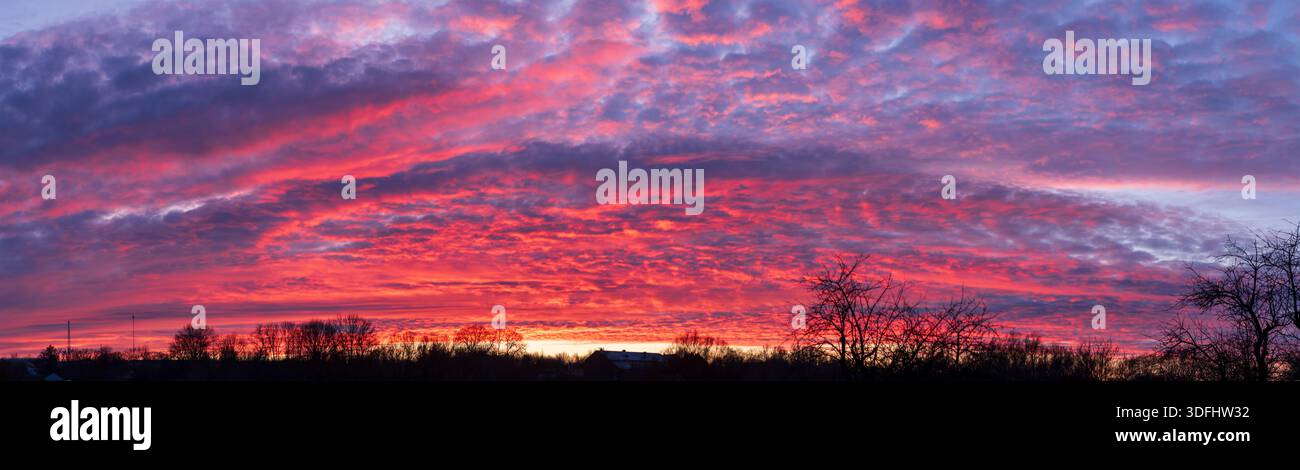 Wide panoramic view of a dramatic fiery sunset with vivid red and ...