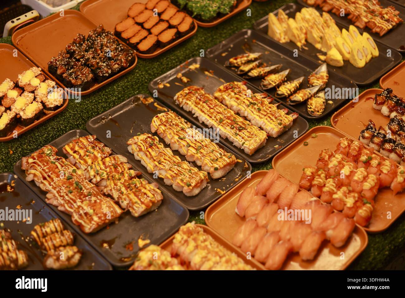 Delicious variety of sushi rolls and nigiri displayed on trays at ...
