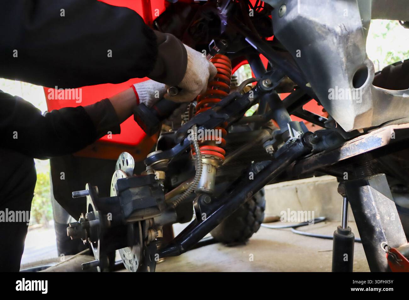 Mechanic hand with gloves carefully fixing suspension coil spring and ...