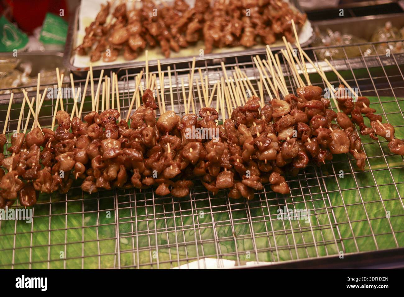 Street food vendor grilling savory barbecue chicken skewers metal rack ...