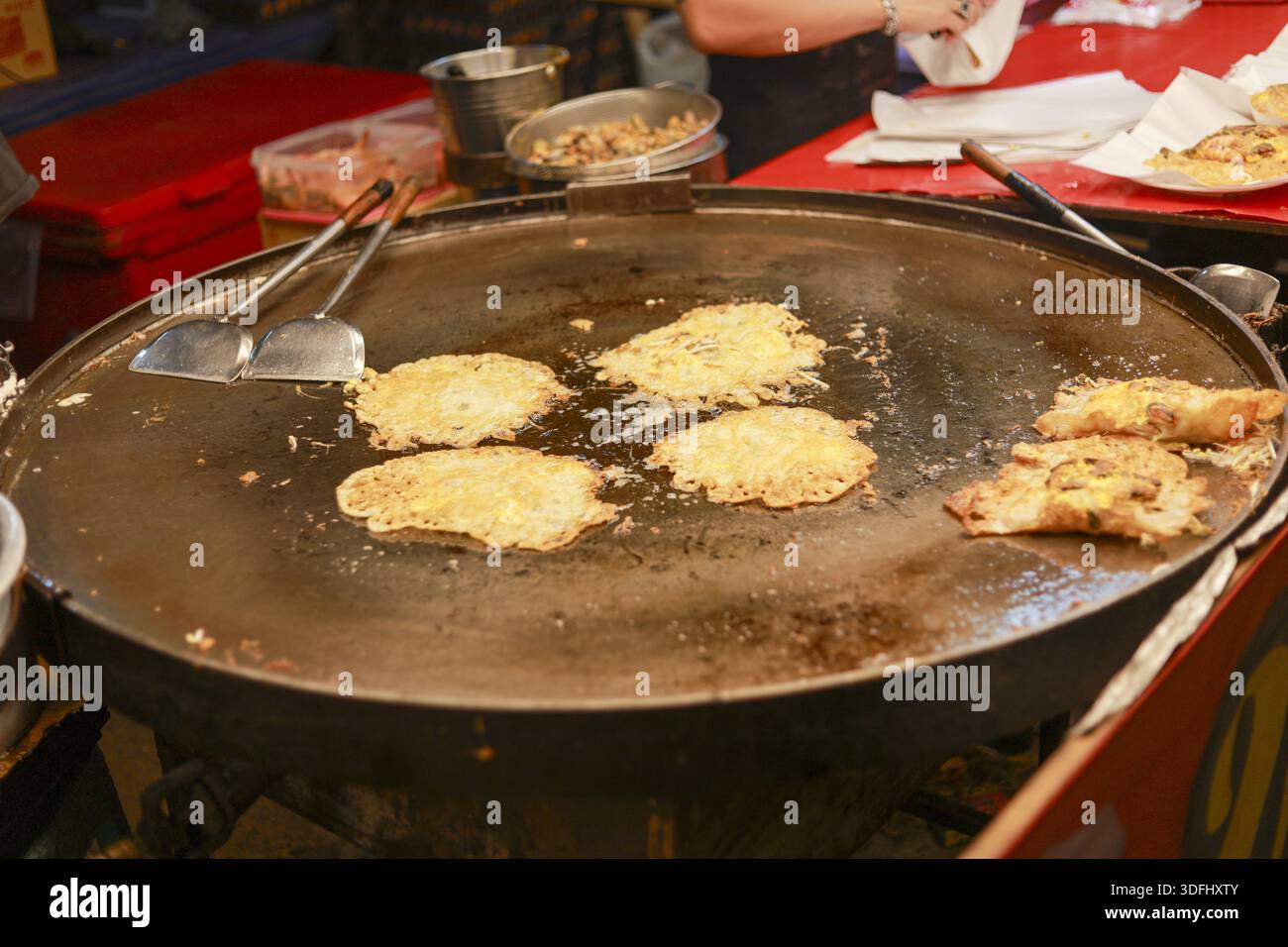 Sizzling hot oyster omelette frying large round pan with spatula lively ...