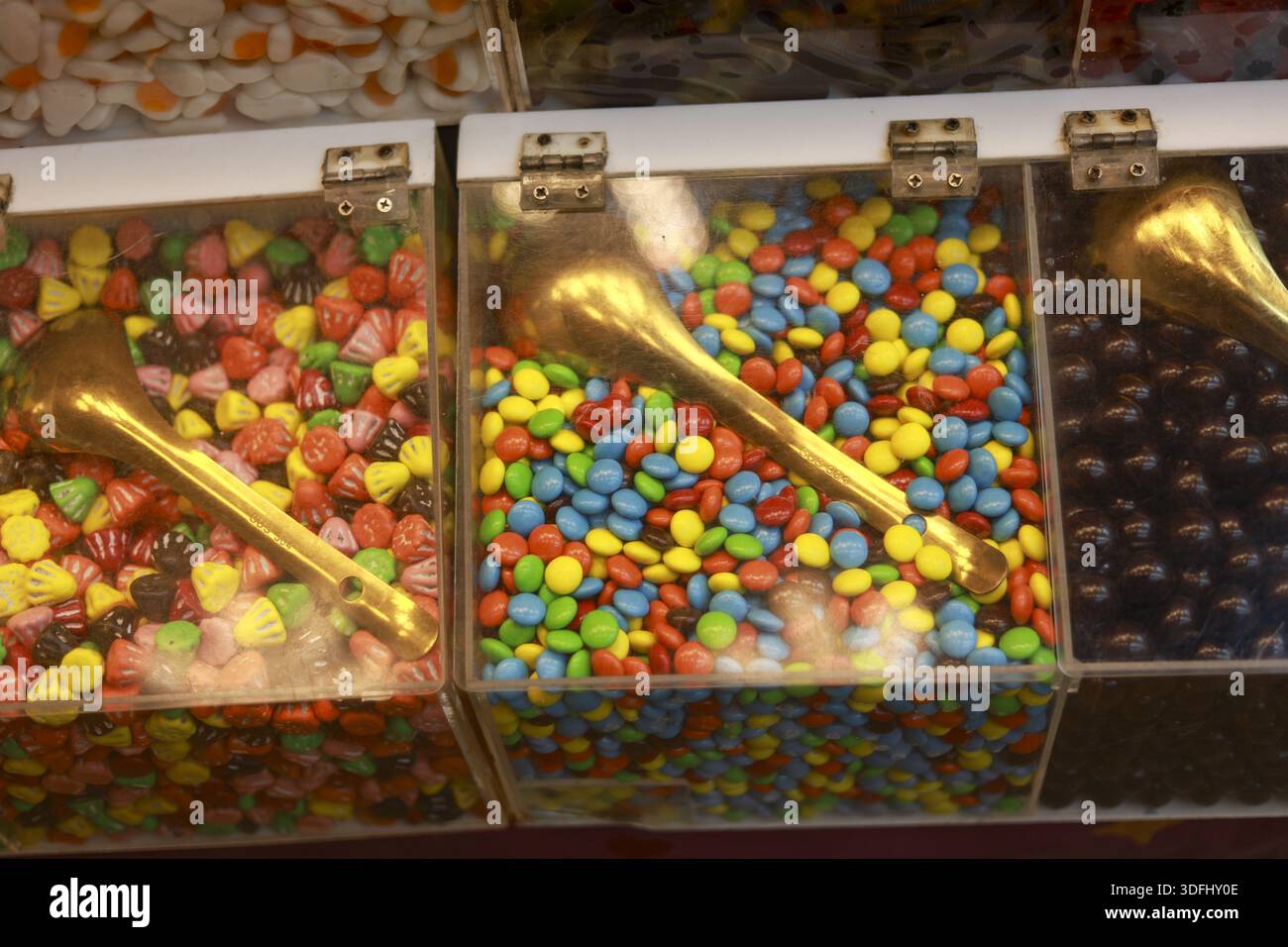 Colorful sweet candy coated chocolate confectionery with golden scoop ...