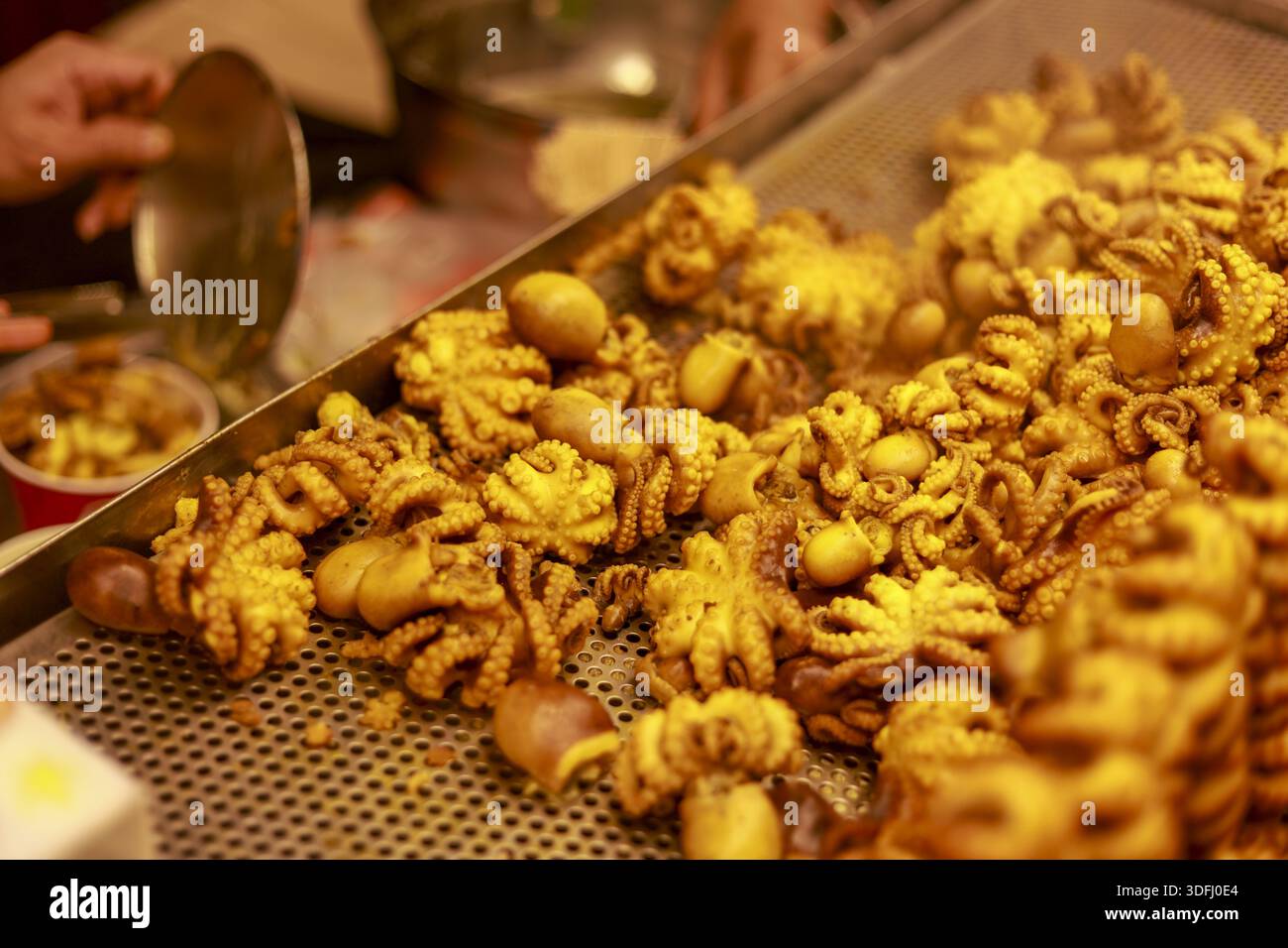 Delicious golden fried baby octopus on metal tray at busy night market ...