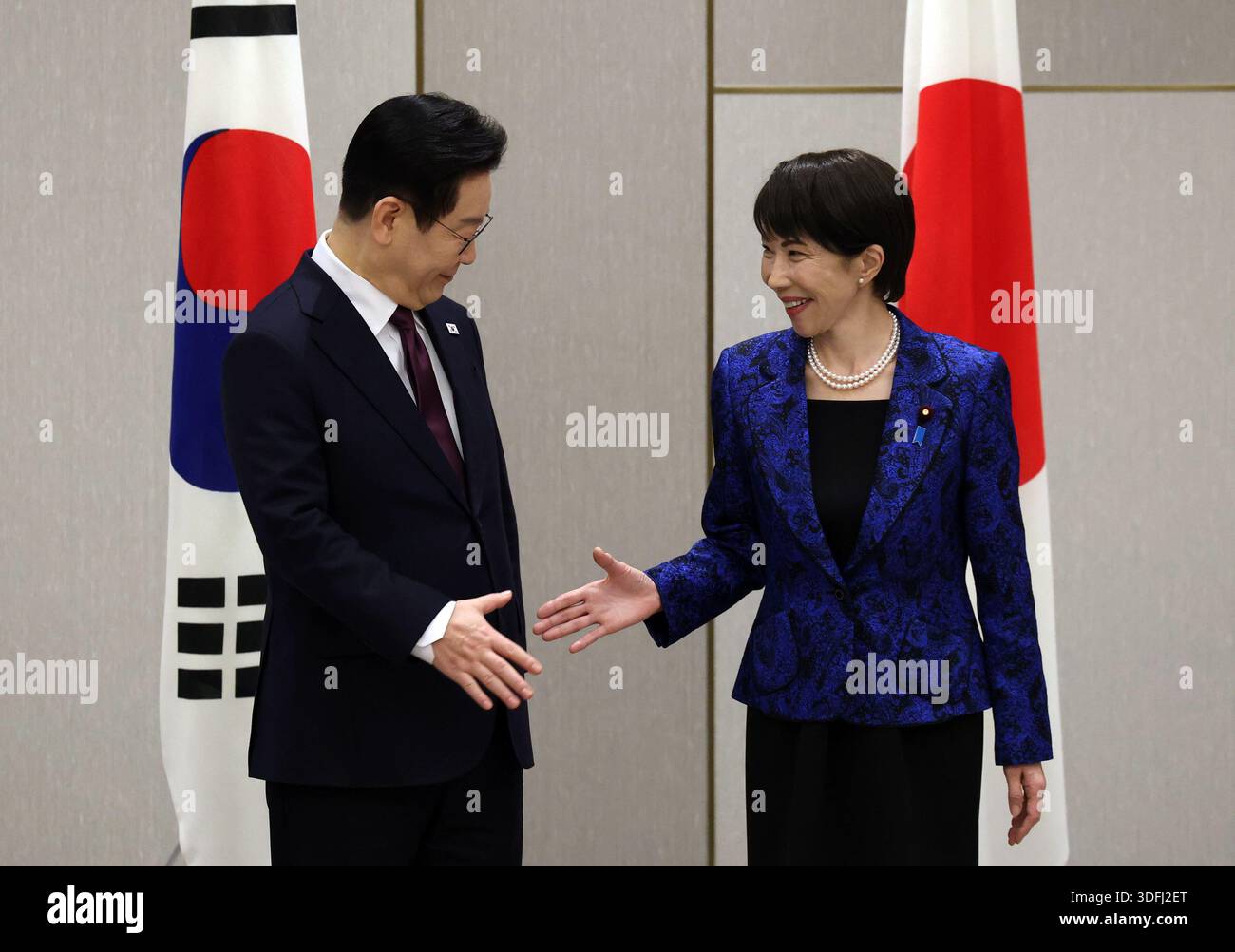 Japan's Prime Minister Sanae Takaichi, right, reaches out to shake ...