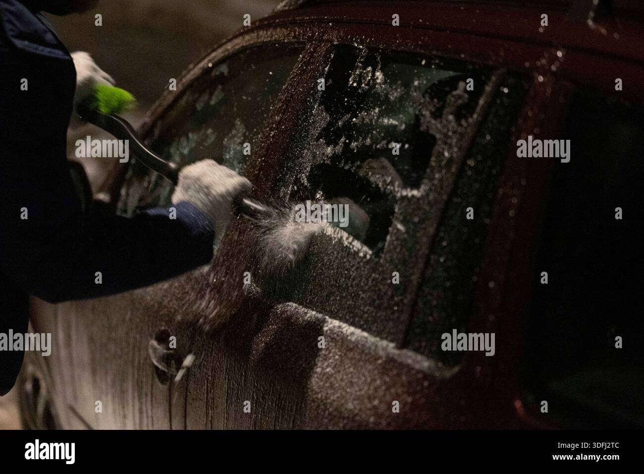 13 January 2026, Saxony, Meißen: A man scrapes his car windows clear in ...