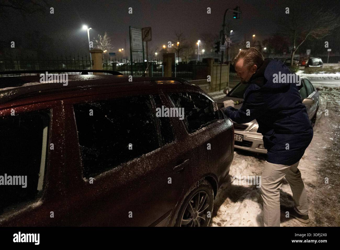 13 January 2026, Saxony, Meißen: A man scrapes his car windows clear in ...