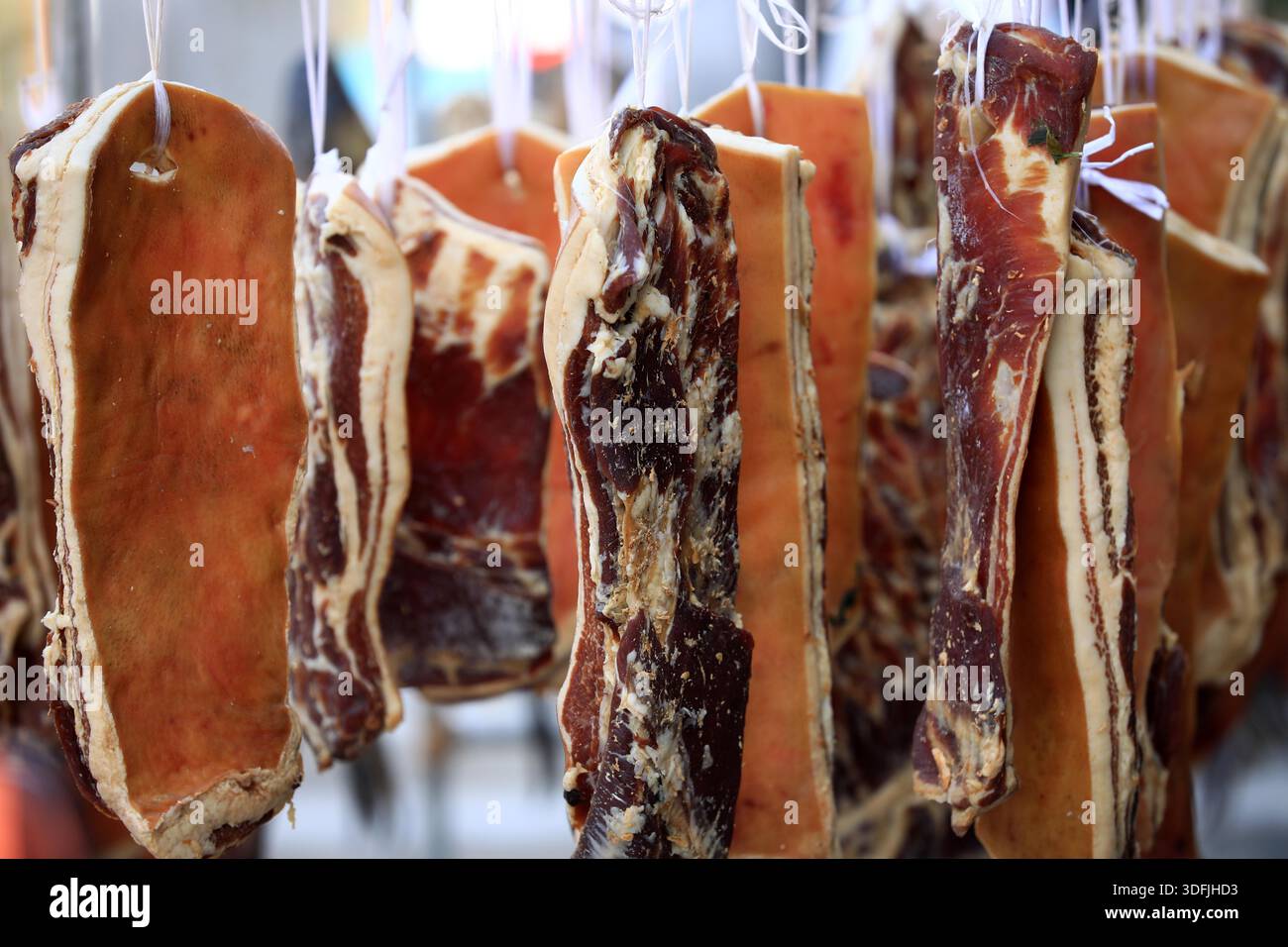 Vendors display and sell traditional cured meats including sausages ...