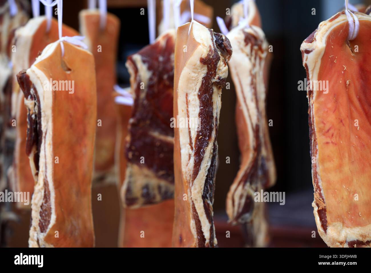 Vendors display and sell traditional cured meats including sausages ...