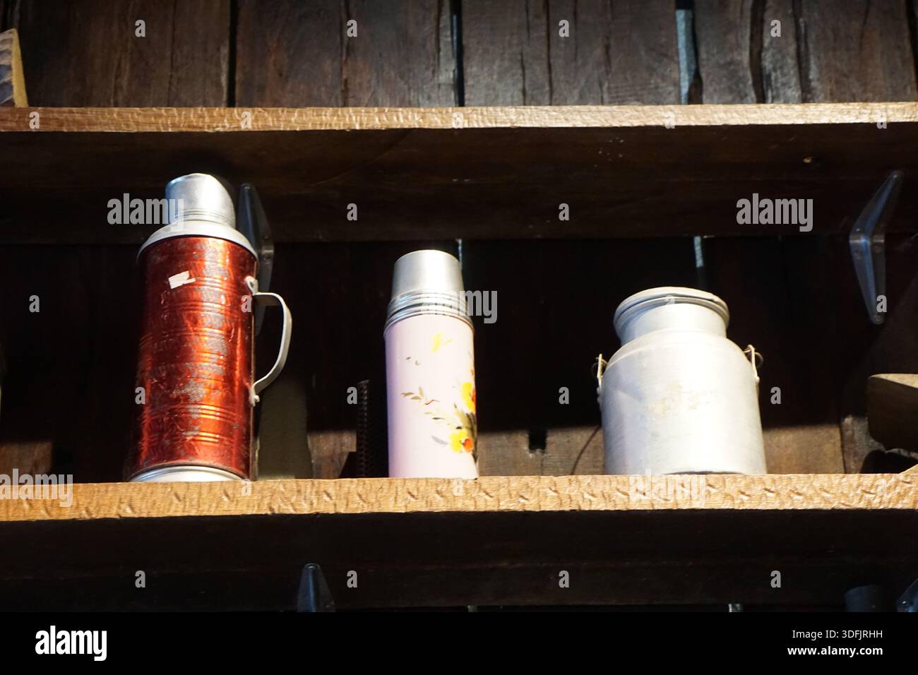 Three retro beverage containers—two thermoses and a milk can—arranged ...