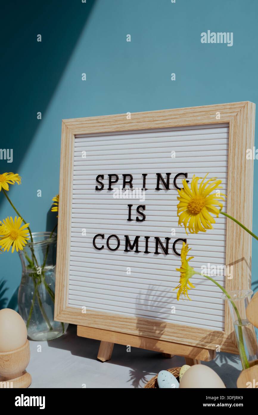 SPRING IS COMING text on letter board with bunny wooden figures and ...